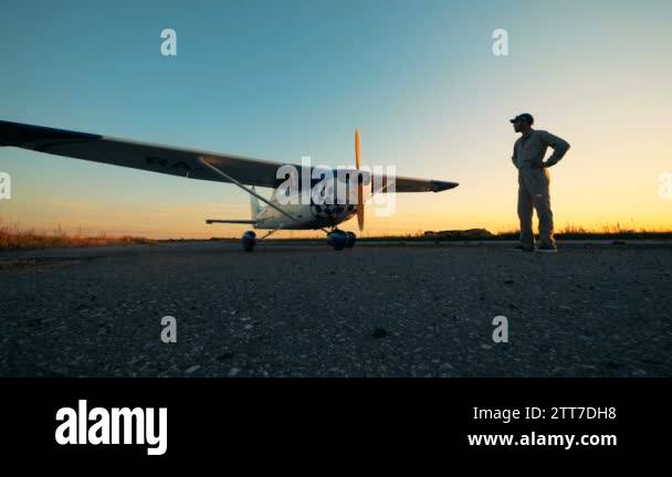 Aviator looking at a plane. Male pilot stands on a runway, looking at a ...