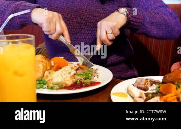 Two women wearing sweaters eating carvery meal consisting of roasted ...