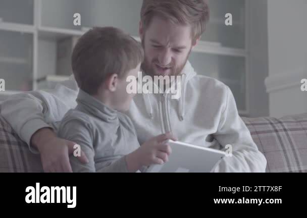 Little smiling boy grabbed his father by the nose and pull it, both are ...