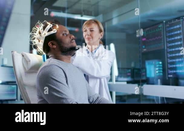 Man Wearing Brainwave Scanning Headset Sits in a Chair while Scientist ...