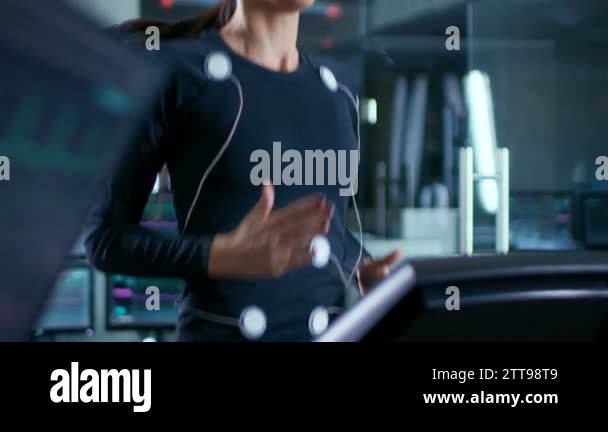 Beautiful Woman Athlete Walks on a Treadmill with Electrodes Attached ...