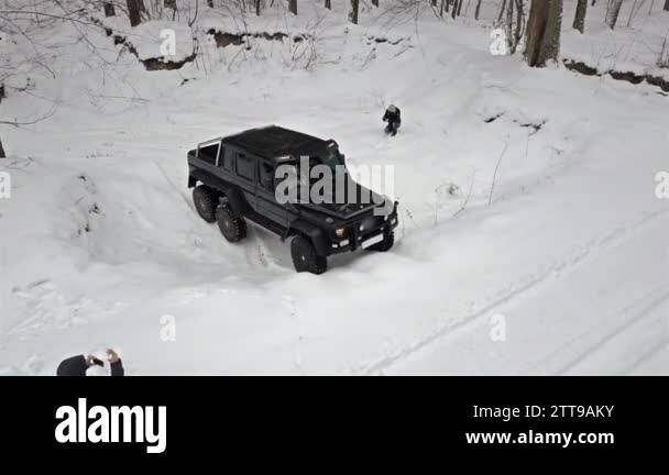 SUV to ride out of a deep pit in the snow-covered road in winter forest ...