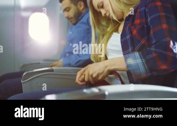 On a Plane Beautiful Blonde Female and Handsome Hispanic Male Fasten They're Seat Belts and ...