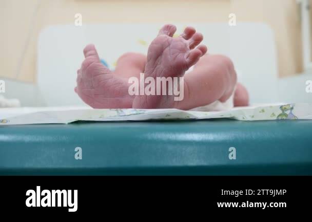 Newborn baby girl lying on back. Baby is kicking and stretching legs ...