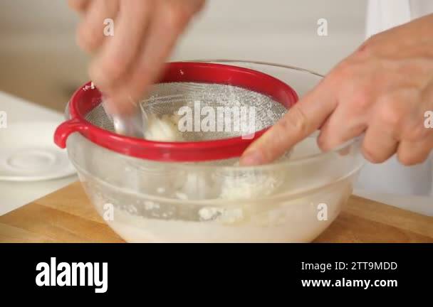 Sifting and mashing strained curd while making dough for backery Stock ...