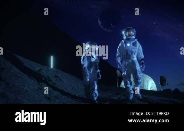 Two Astronauts in Space Suits Exploring Newly Discovered Planet. In the Background Space Base ...