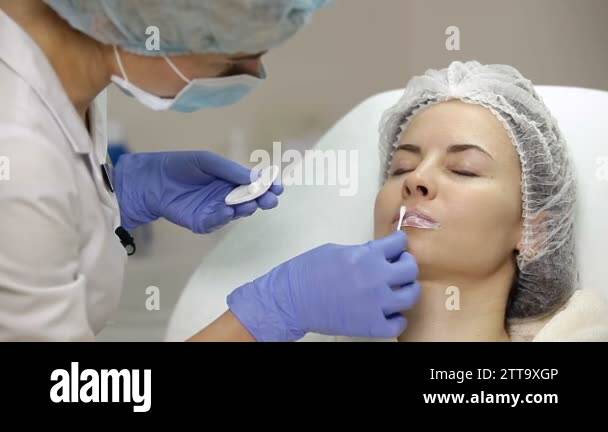 Beautician applies anesthetic cream on t lips of patient before ...