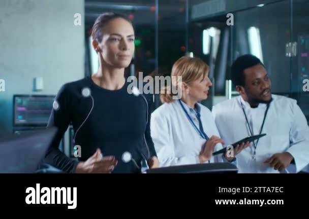 Beautiful Woman Athlete Runs on a Treadmill with Electrodes Attached to ...