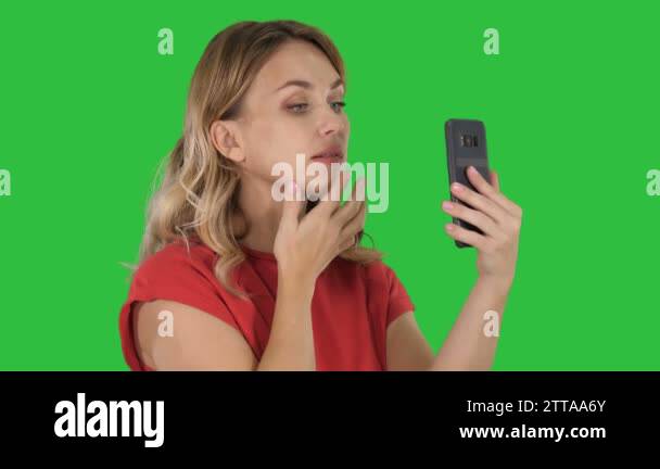 Beautiful woman preen using her phone like a mirror on a Green Screen ...