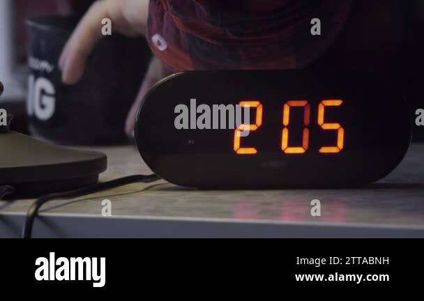 Black rectangular shaped electronic digital clock shows time in orange ...