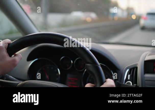 Close-up of steering wheel with hands on it and automobile dashboard ...