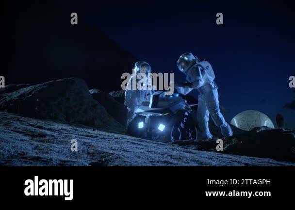 Two Astronauts in Space Suits on an Alien Planet Prepare Space Rover for Surface Exploration ...