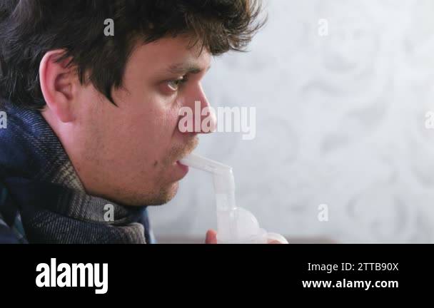Use nebulizer and inhaler for the treatment. Sick man inhaling through ...