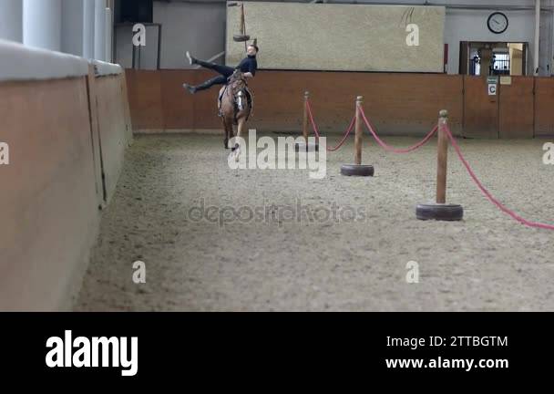 A man trick riding a horse on arena. Man doing stunts on horseback. Man ...