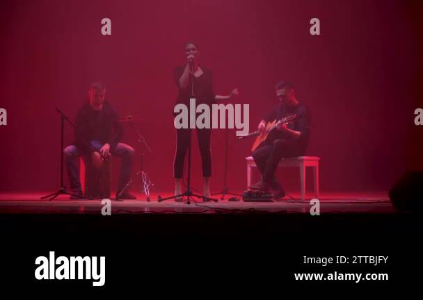 Music band performing on stage in red light and smoke in background ...