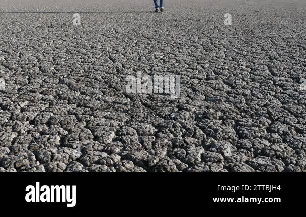 Man in jeans and boots walking on dry cracked land after drought Stock ...