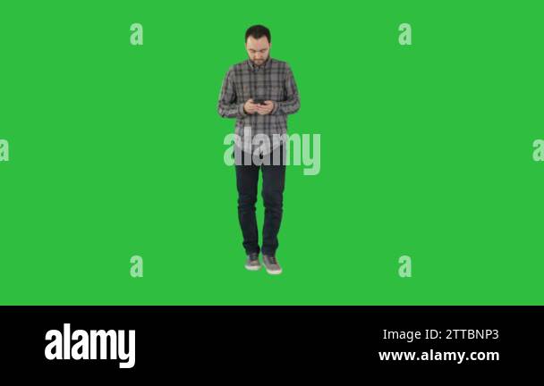 Young man walking and using a phone, messaging on a Green Screen ...