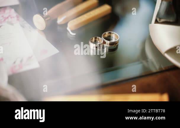 Two gold wedding rings lying on a table whit decorations shining with ...