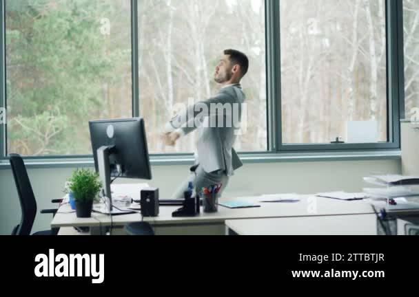 Good-looking bearded man in suit is dancing in office room alone moving ...