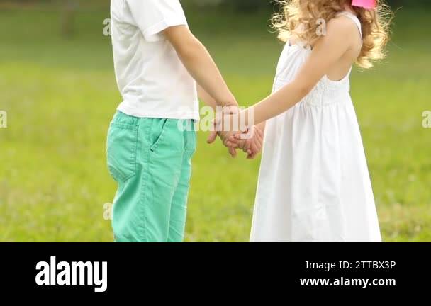 Children hold hands, the girl is embarrassed and smiles. Slow motion ...