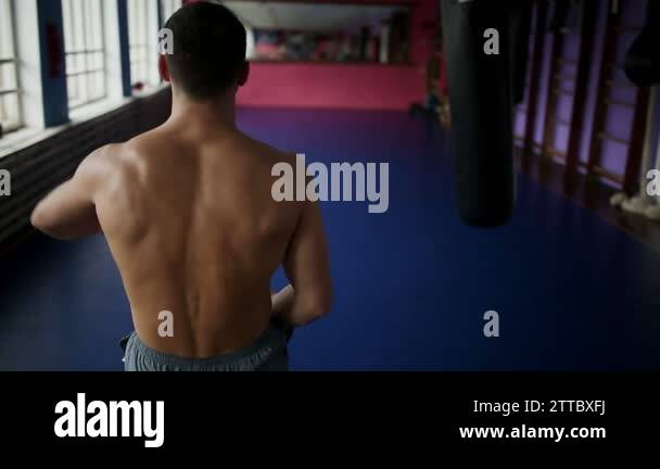Rear view of male boxer makes punches for bag Boxing gloves at the gym ...
