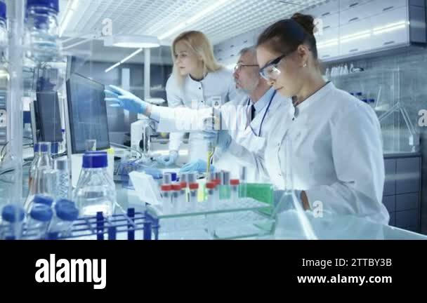 Team of Research Scientists Working With Personal Computer, Analysing ...