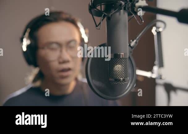 young asian singer singing in recording studio with headphone and ...