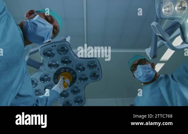 Low Angle Shot POV Patient View: Two Professional Surgeons Turning on ...
