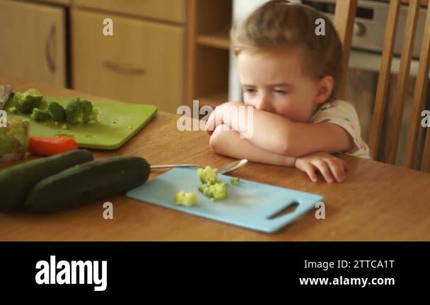 Little girl in the kitchen. She is upset, crying, hiding her face. Not ...