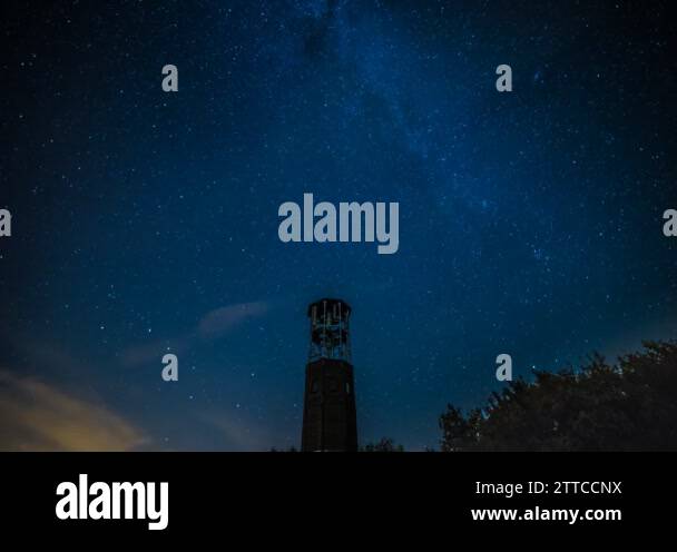 A lookout tower under a night sky full of stars and small clouds Stock ...