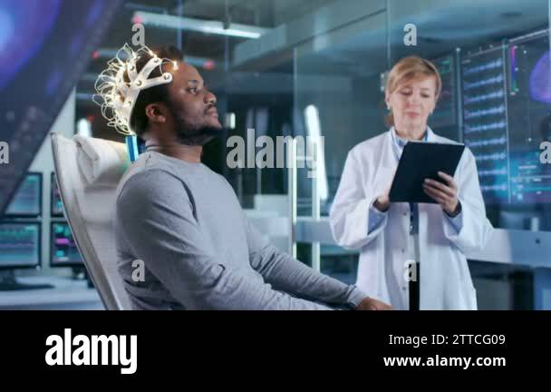 Man Wearing Brainwave Scanning Headset Sits in a Chair while Scientist ...