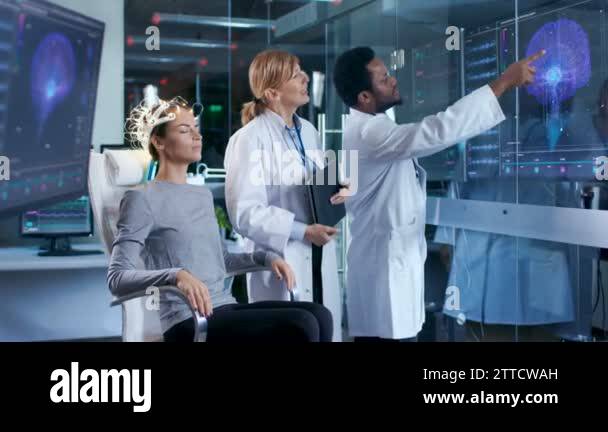 Woman Wearing Brainwave Scanning Headset Sits in a Chair while Two ...