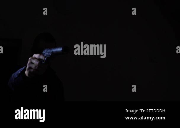 Man pulling out his gun in the darkness and aiming at the camera. 4k ...