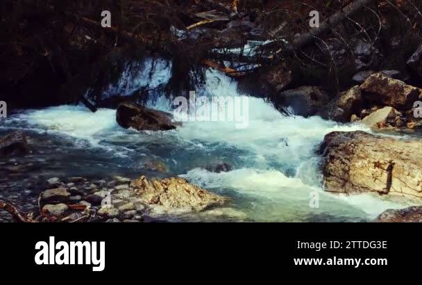 A river flows over rocks in this beautiful scene in the Alps mountains ...