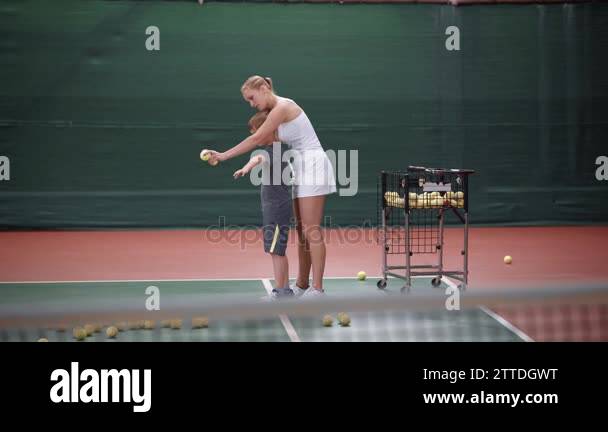Professional female tennis player standing behind her little apprentice ...