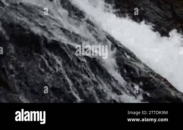 tilt down of waterfall falling and hit rock splashing to river Stock ...