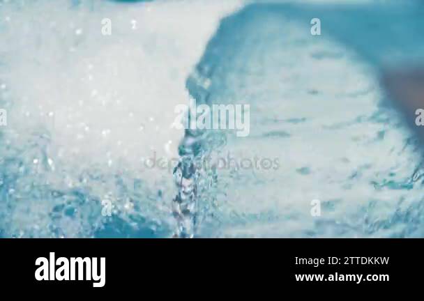 Arc of water pouring into blue swimming pool from metal waterfall Stock ...