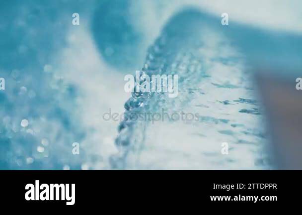 Slow motion curve of water pouring into blue swimming pool from metal ...