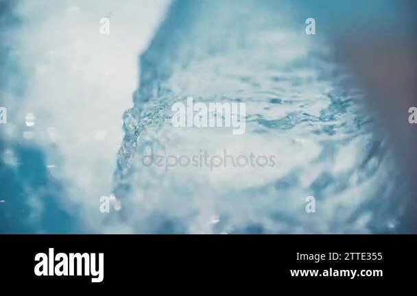 Curve of water pouring into blue swimming pool from metal waterfall ...