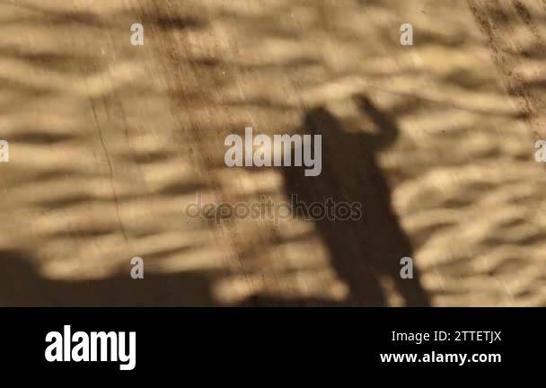 Shadow of man waving a hand goodbye on slow wave reflection pattern ...