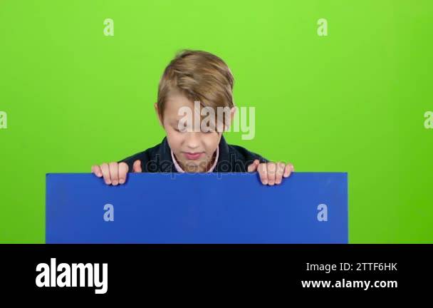 Child boy appeared from behind a blue poster to look at him hiding ...