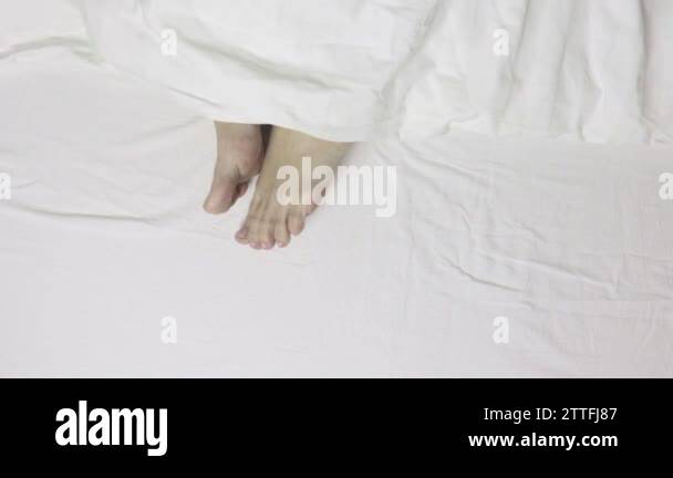 Woman legs feet lying in bed, top view, morning waking up and relaxing ...