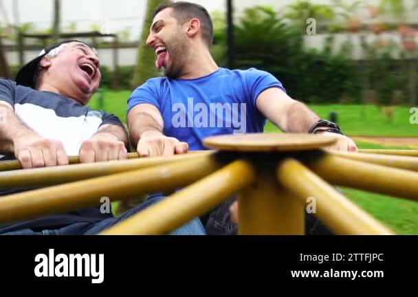 Dad and son playing on roundabout Stock Video Footage - Alamy