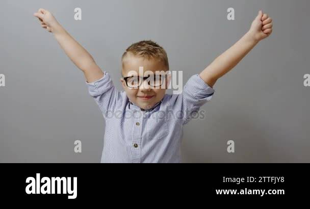 Portrait of the funny cute little boy in the glasses rising hands up ...