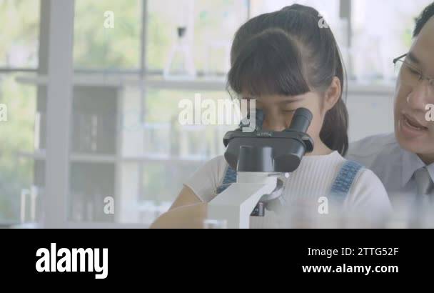 Asian male scientist teaching little girl scientific experiment using ...