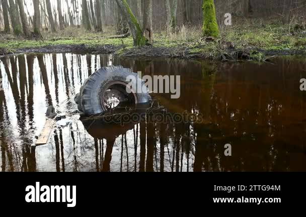 Old tyre and other garbage lies on the waterlogged river bank ...