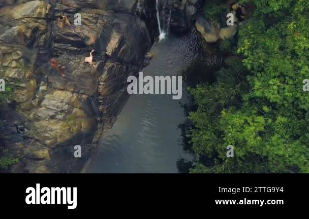 Tourist people diving and swimming in mountain waterfall in rainforest ...