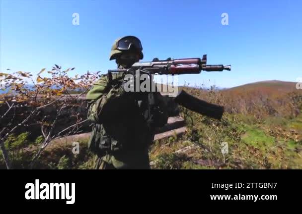 Soldier reloading his AK rifle. Hills and ocean on background Stock ...