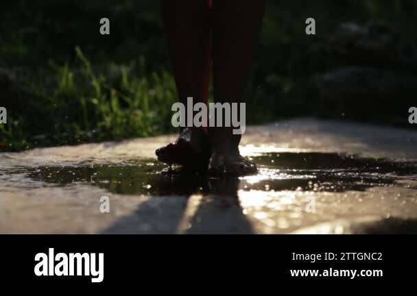 Female feet barefoot in a puddle in backlight. Silhouette of female ...