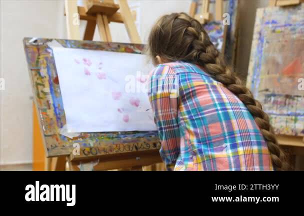 Young cute Female Artist is in an Art Studio, Sitting Behind an Easel ...